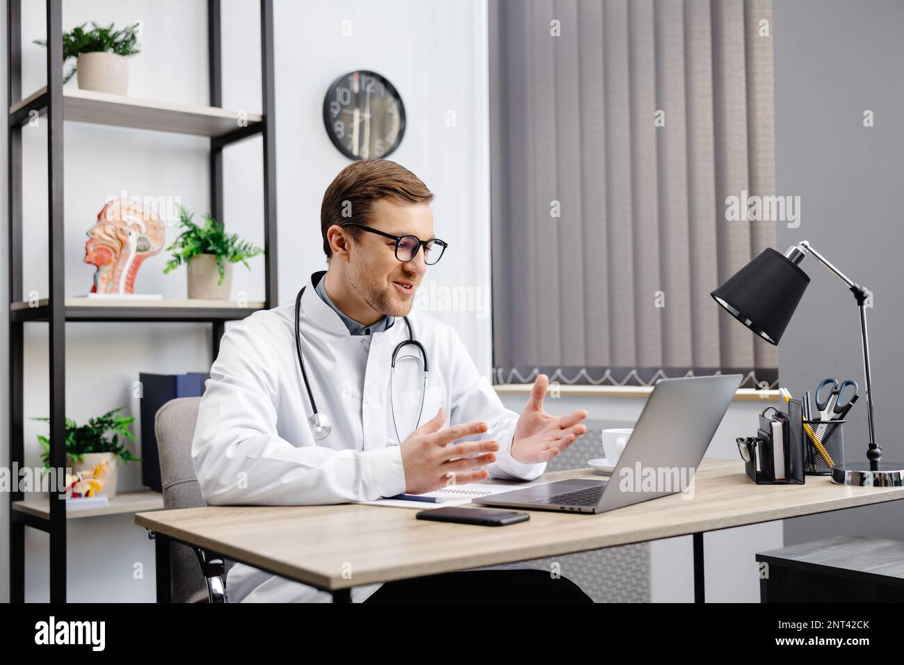 Portrait of man doctor talking to online patient on laptop screen ...