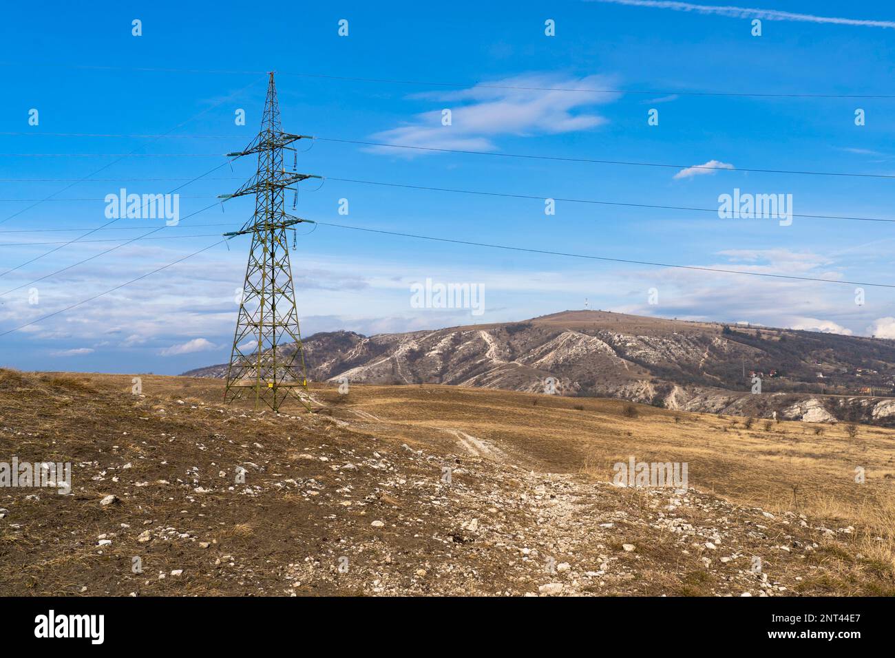 Tower of high voltage transmission lines with rocky barren mountain in ...
