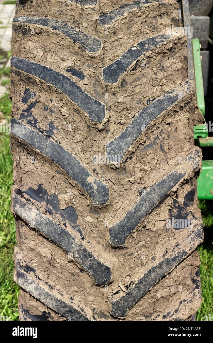 Dirty tire of a large tractor covered in mud after ploughing work on ...