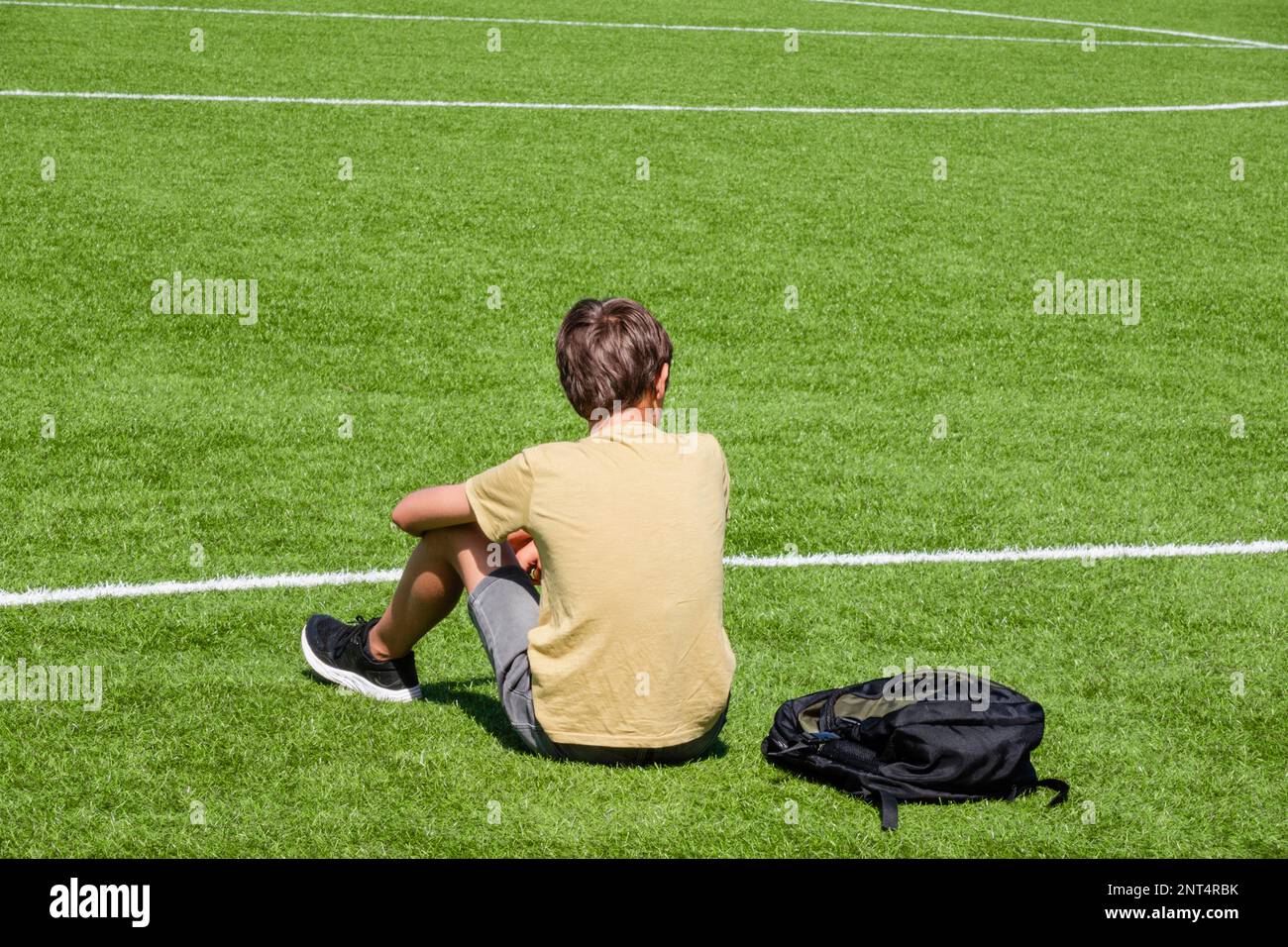 Tired sad alone teenage boy with backpack sitting in empty sport ...