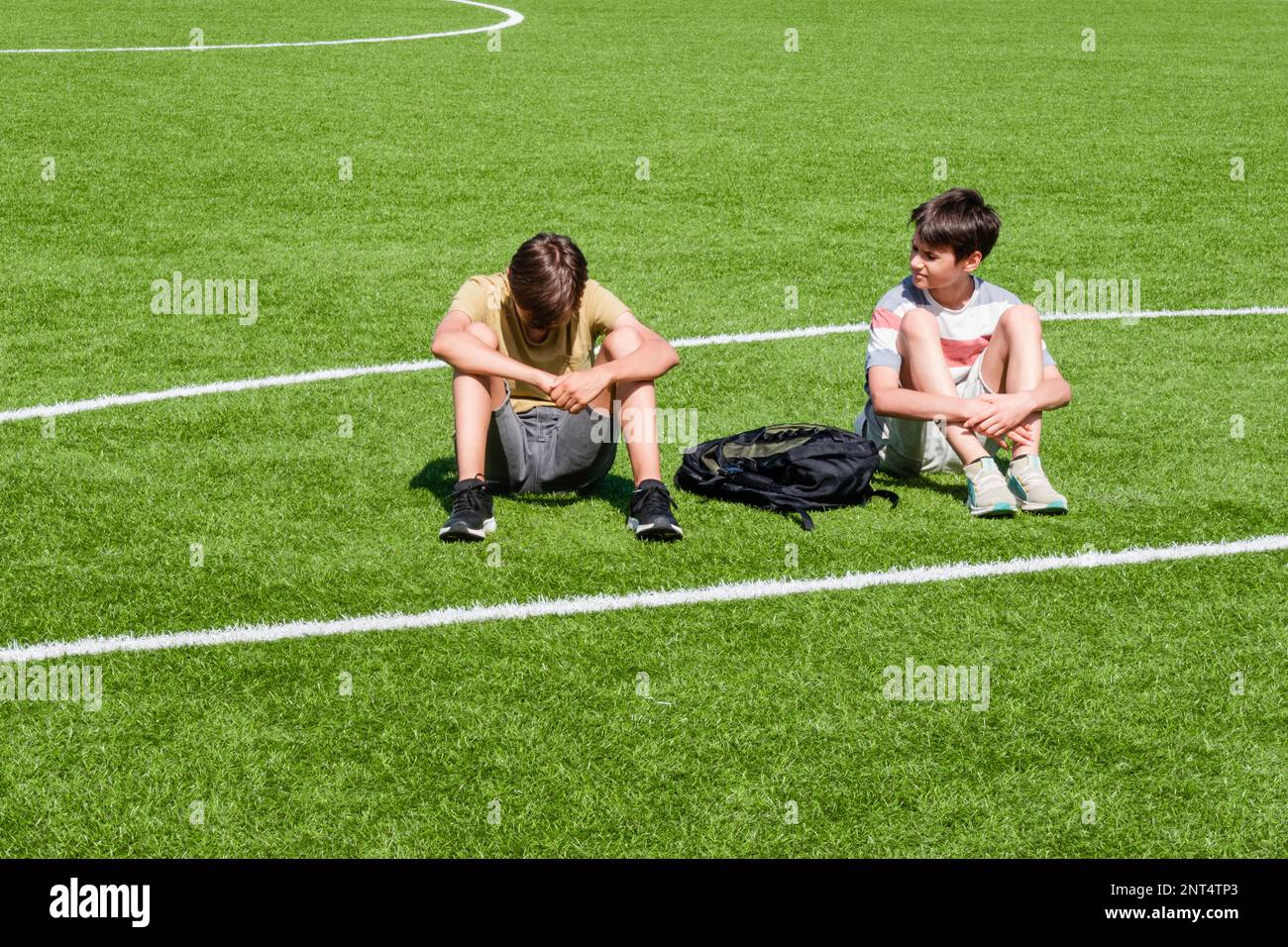 Teenage boy comforting consoling upset sad friend in school stadium ...