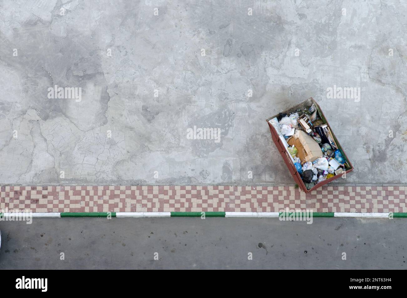 Trash the urn is on the asphalt road next to the sidewalk is filled ...