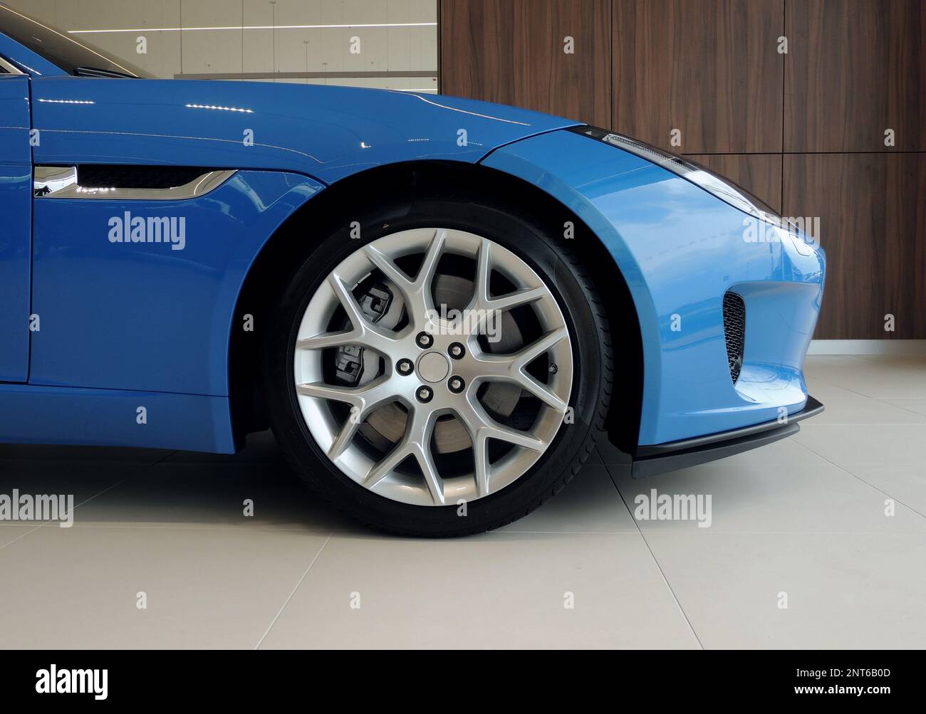 The front part of a sports car on low profile tires in the showroom of ...