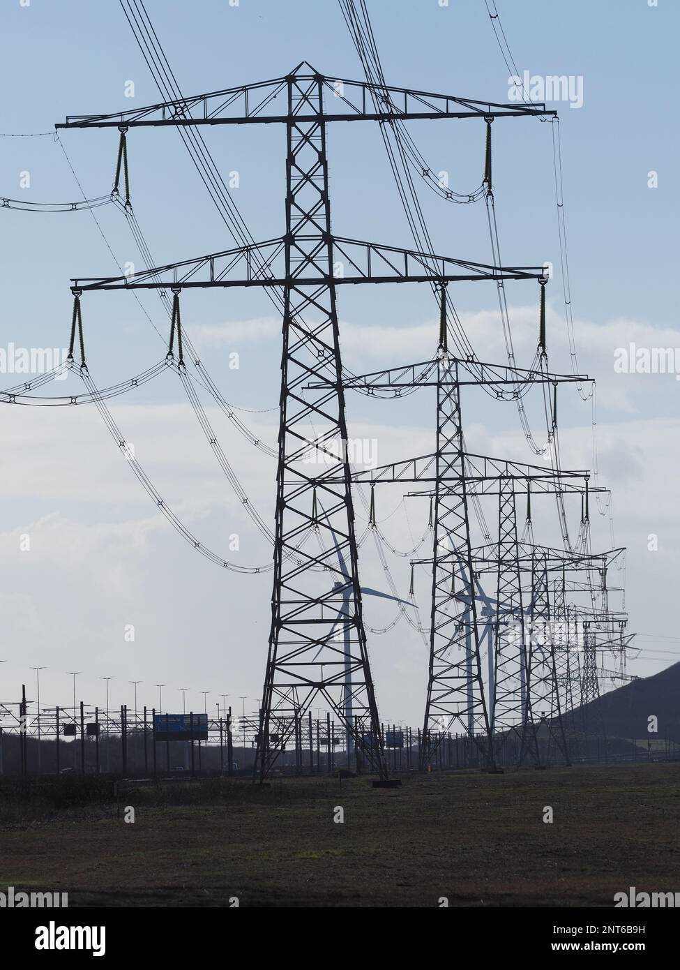 long line of high voltage power electicity lines masts towers in the ...