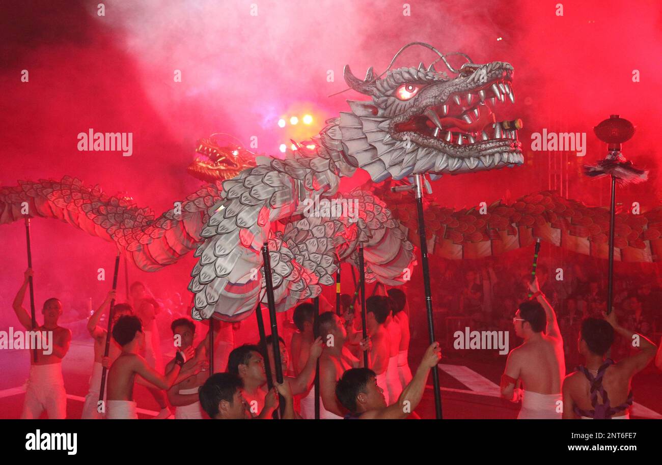 People clad in a loincloth carry a dragon float, portable shrine, and ...