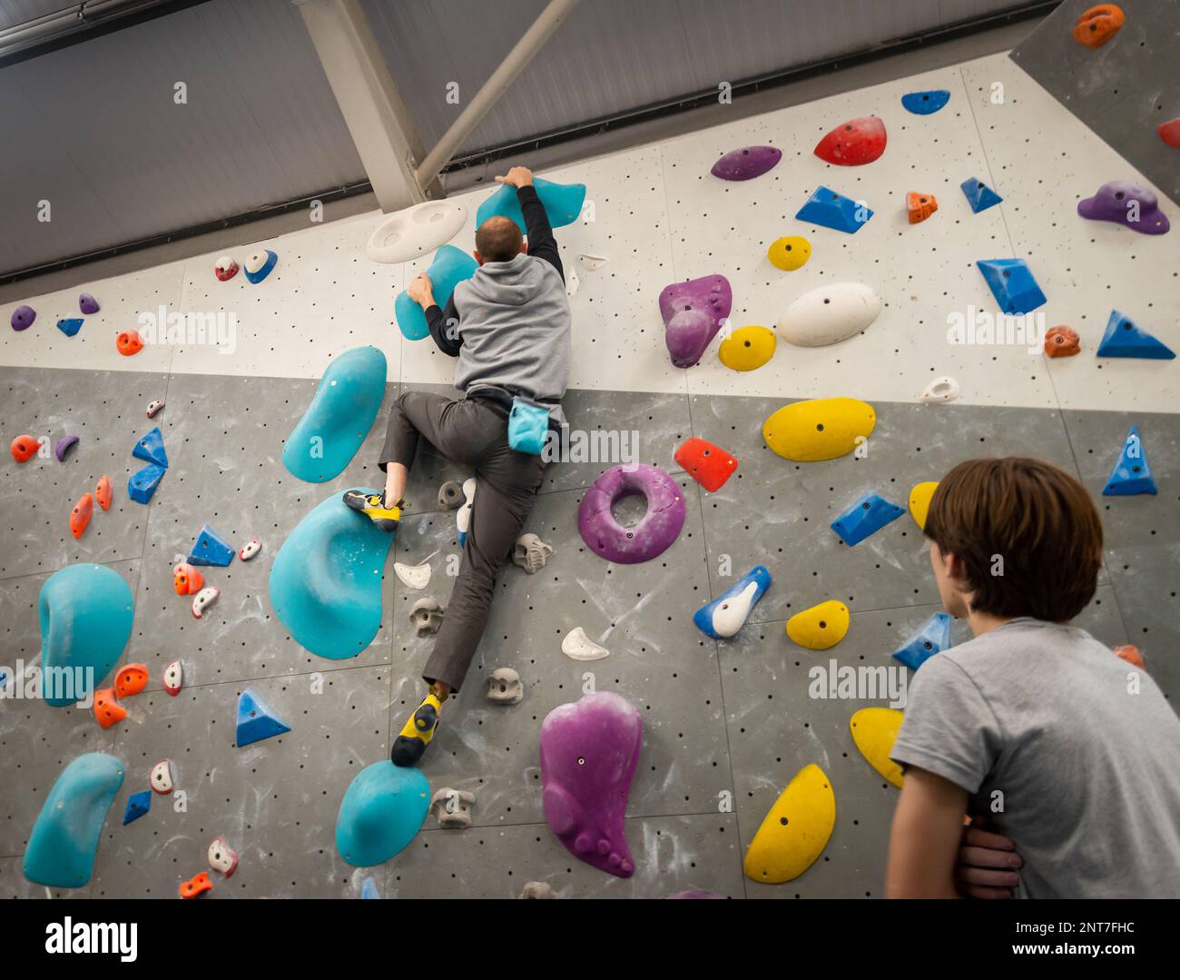 Male climber traversing indoor climbing wall using holds and grips of ...