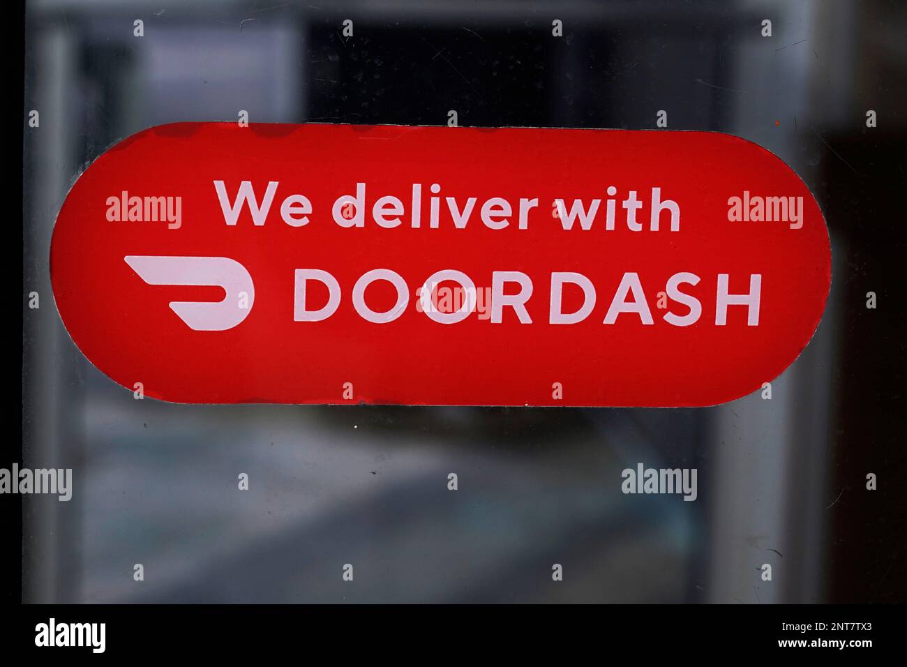 A DoorDash sign is posted on the door of a Dunkin' Donuts franchise ...