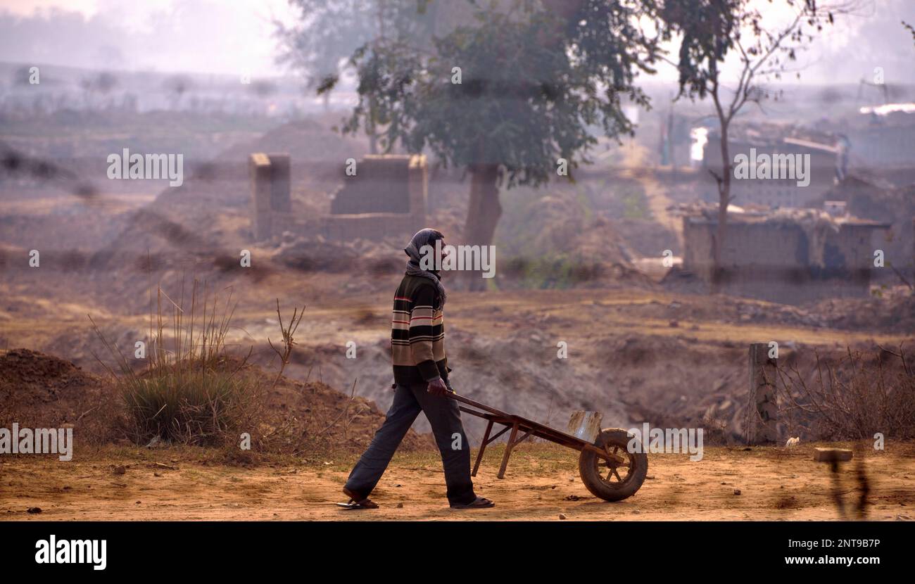 An Indian labourer pushing a cart along a road side in Rajasthan, India ...