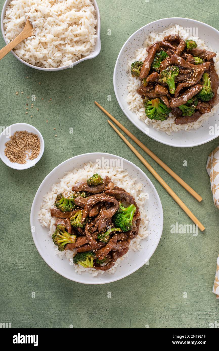 Beef and broccoli served over rice on a plate overhead on green ...