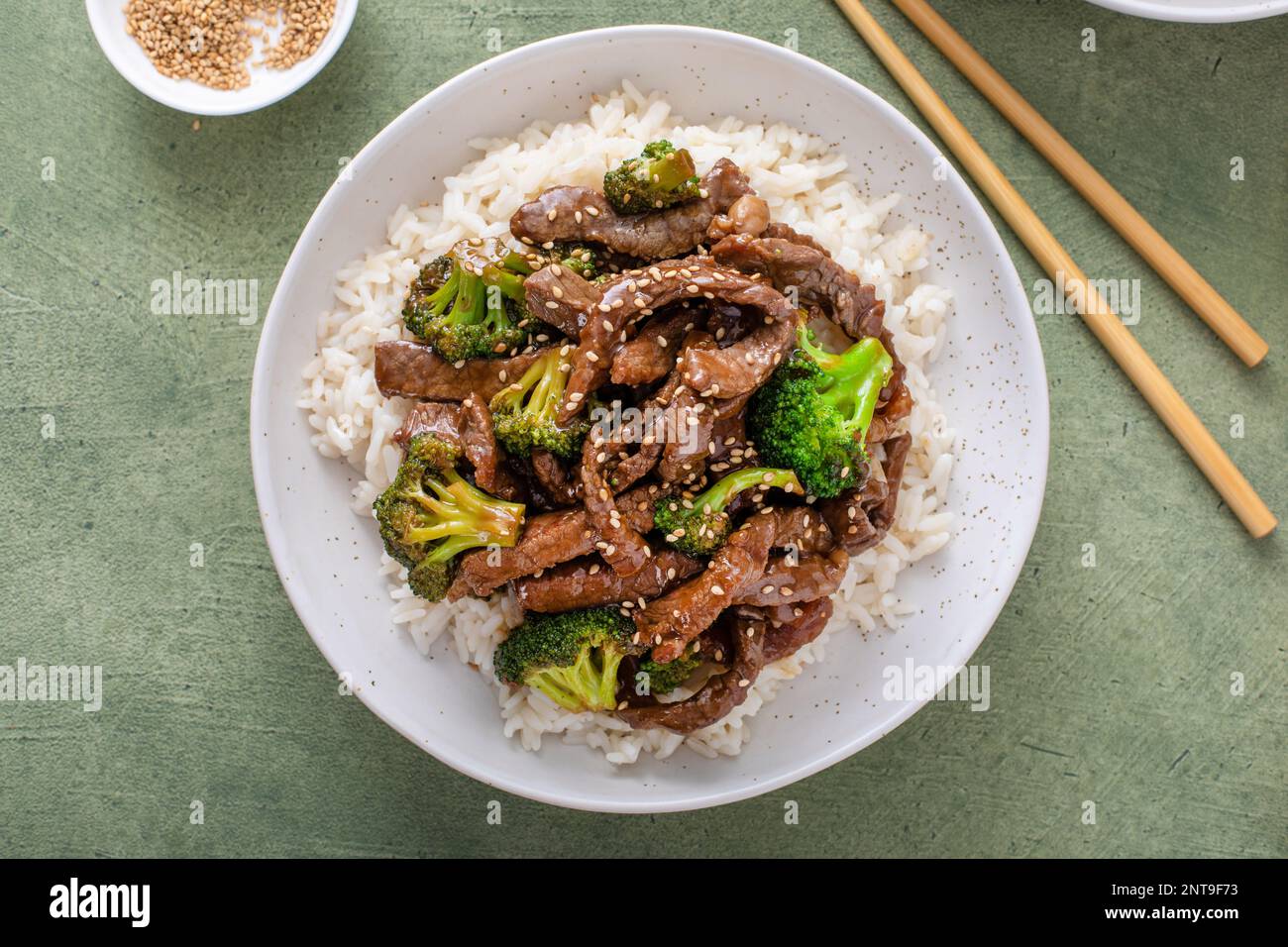 Beef and broccoli served over rice on a plate overhead on green ...