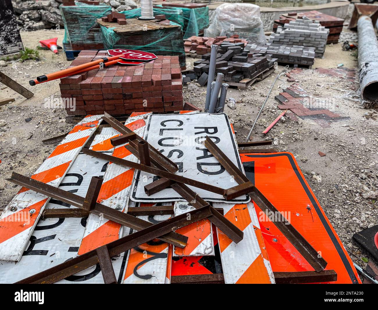 Road closed signs and stop signs sit stacked among bricks and other ...