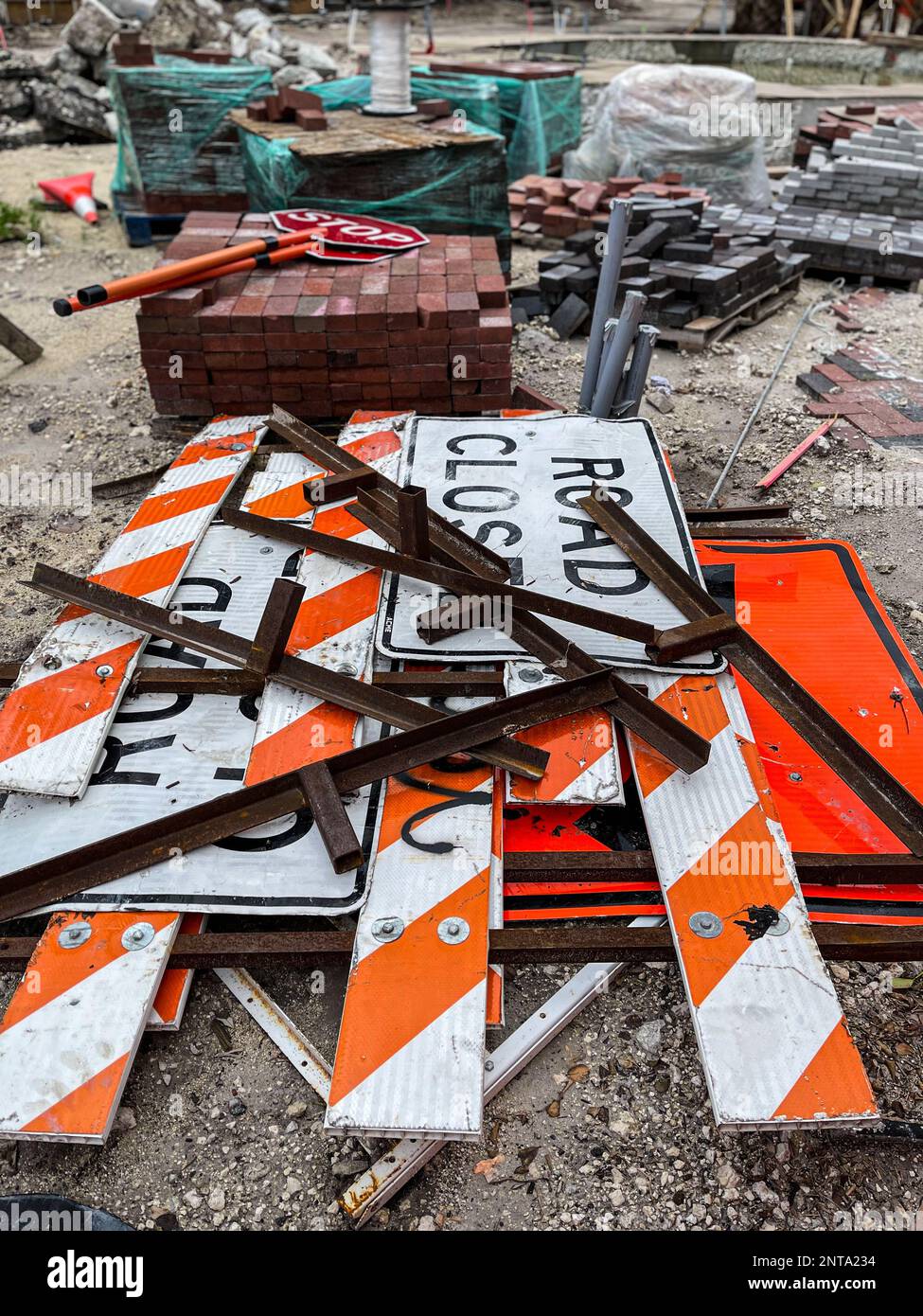 Road closed signs sit stacked among bricks and other supplies at road ...