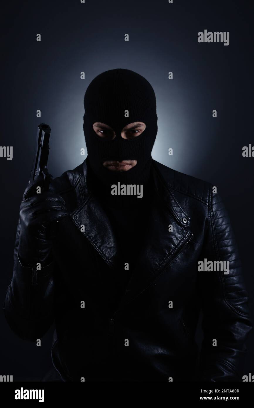 Man wearing knitted balaclava with gun on black background Stock Photo ...