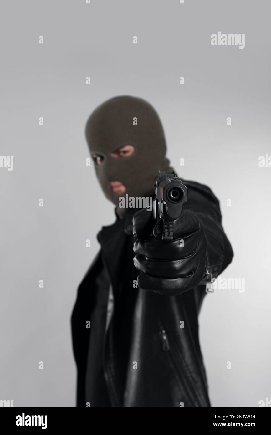 Man wearing knitted balaclava with gun on light grey background Stock ...
