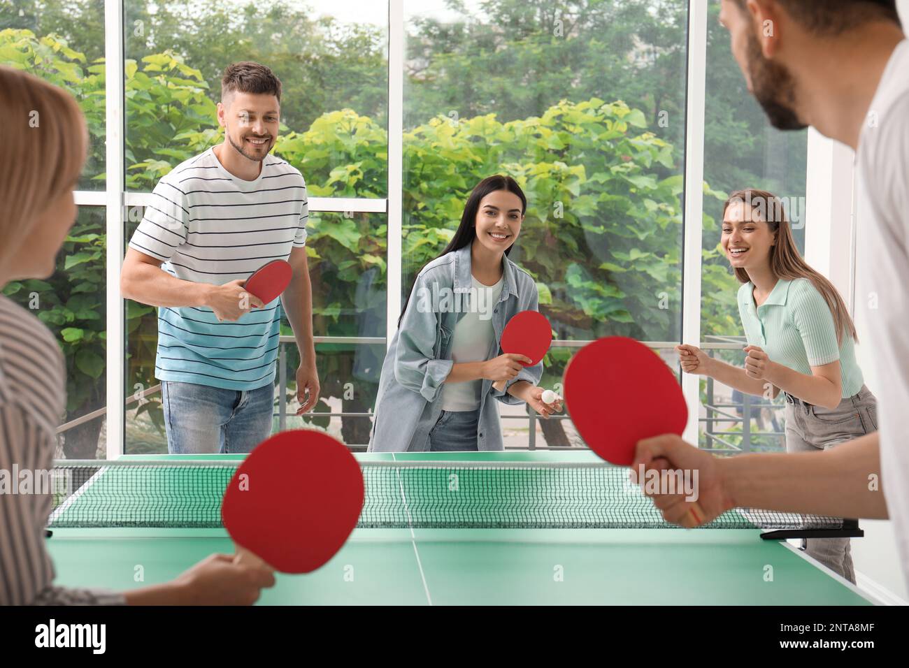 Happy friends playing ping pong together indoors Stock Photo - Alamy