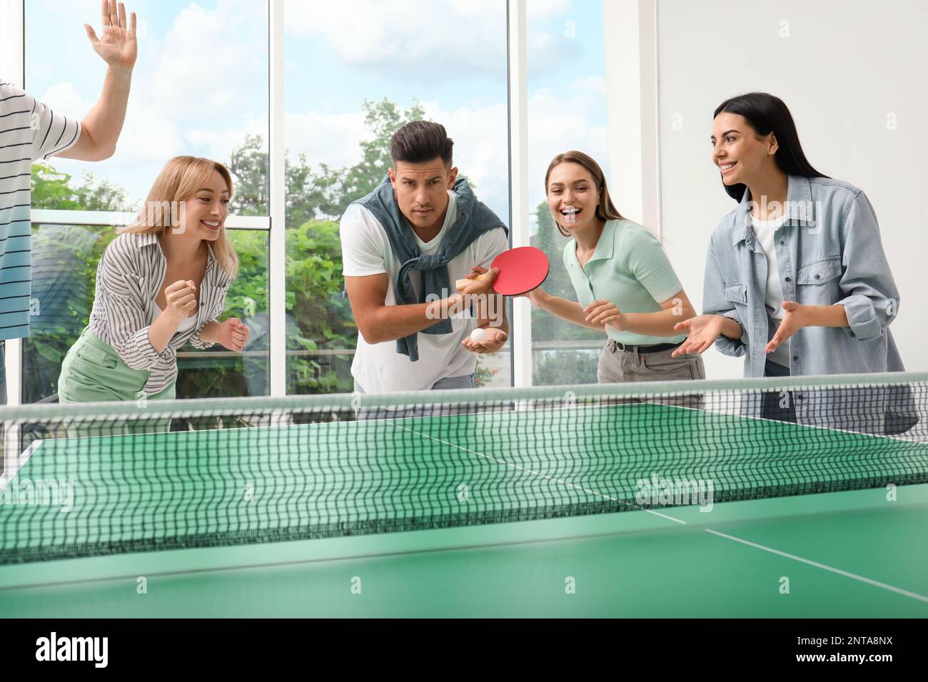 Happy friends playing ping pong together indoors Stock Photo - Alamy