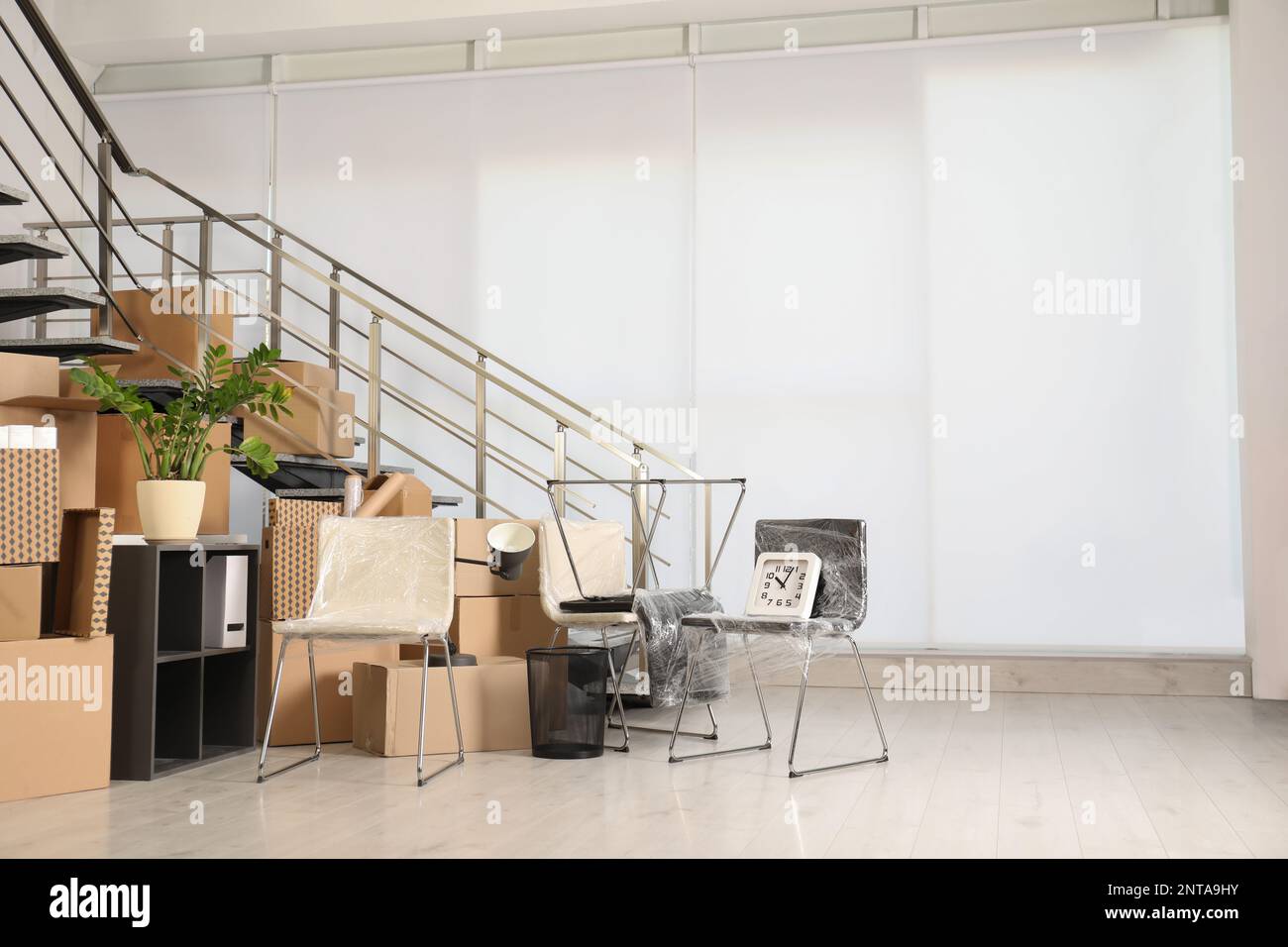 Cardboard boxes and packed stuff near stairs in office, space for text ...