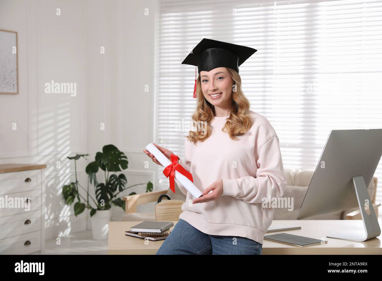 Happy student with graduation hat and diploma at workplace in office ...