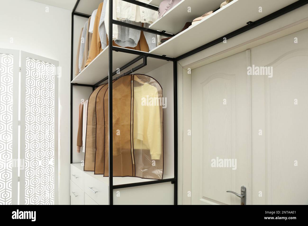 Garment bags with clothes on rack in dressing room. Space for text ...