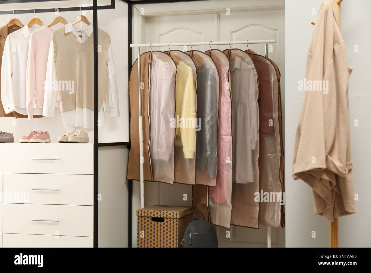 Garment bags with clothes on rack in dressing room Stock Photo - Alamy