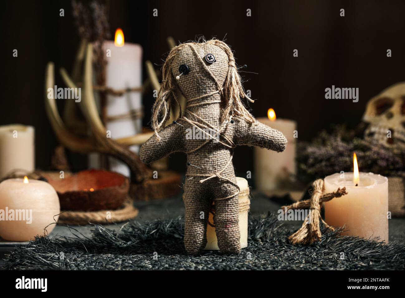 Voodoo doll pierced with pins and candles on table. Curse ceremony ...
