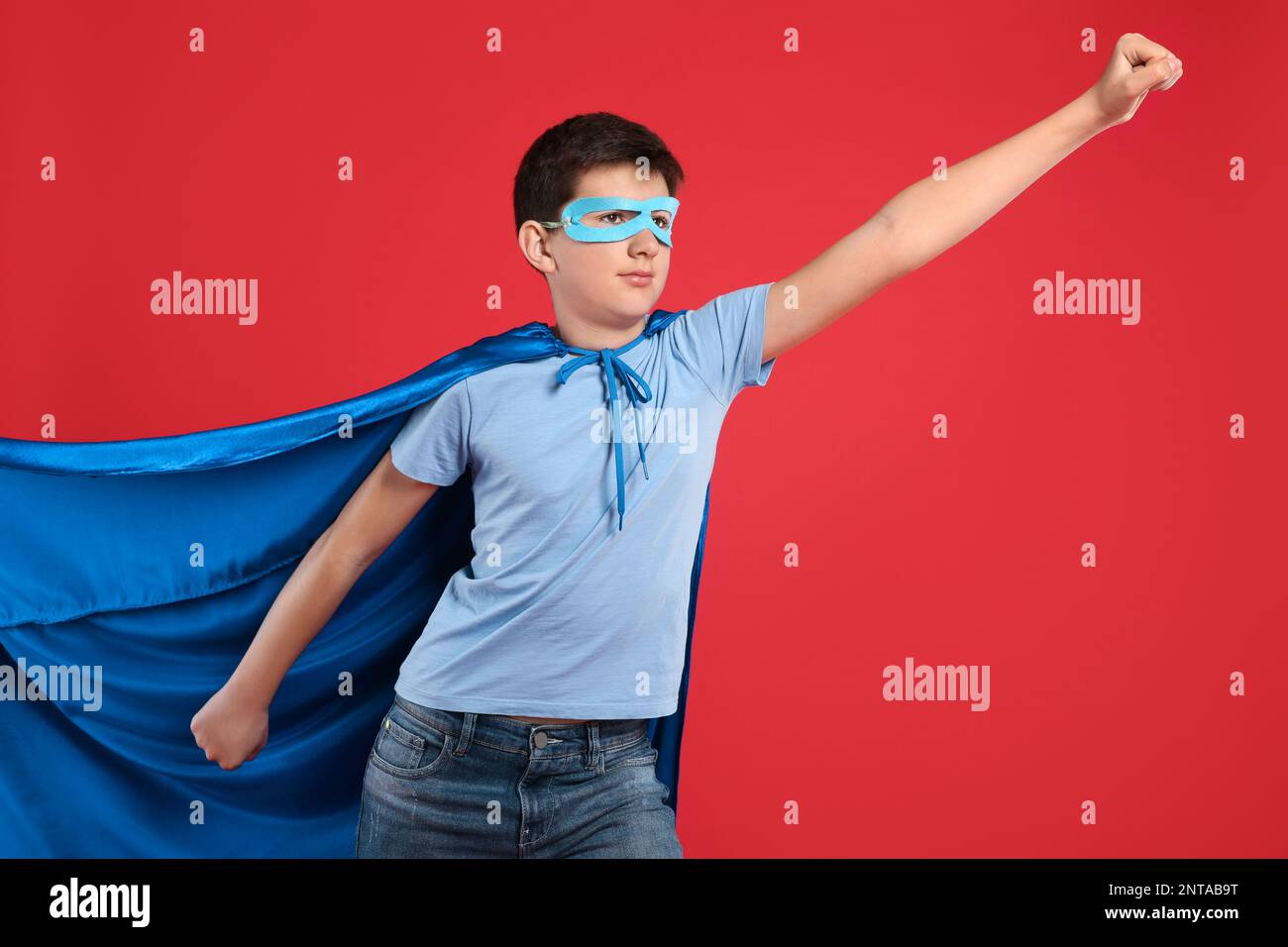 Teenage boy in superhero costume on red background Stock Photo - Alamy