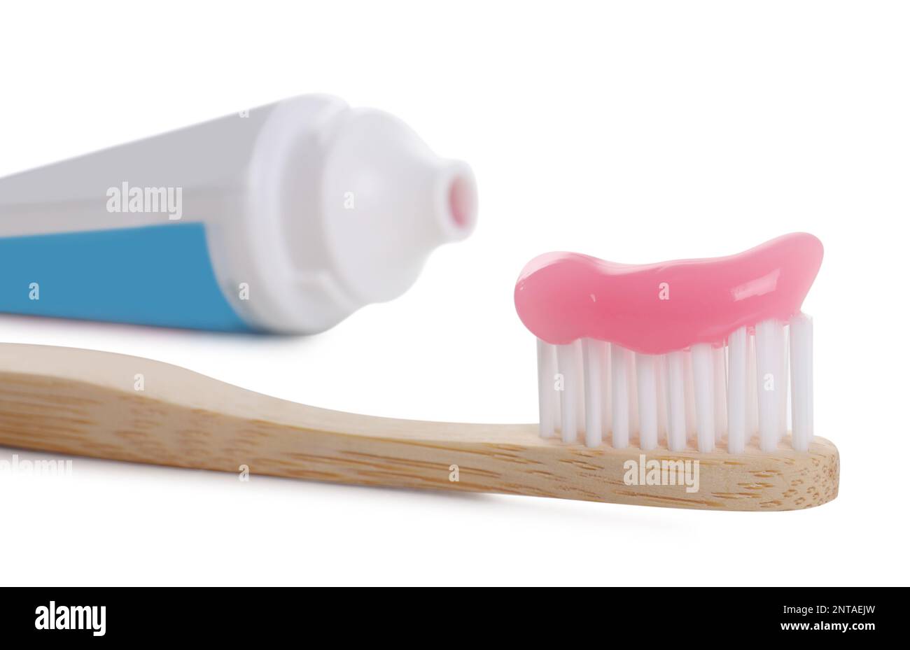 Wooden brush with toothpaste and tube on white background, closeup ...