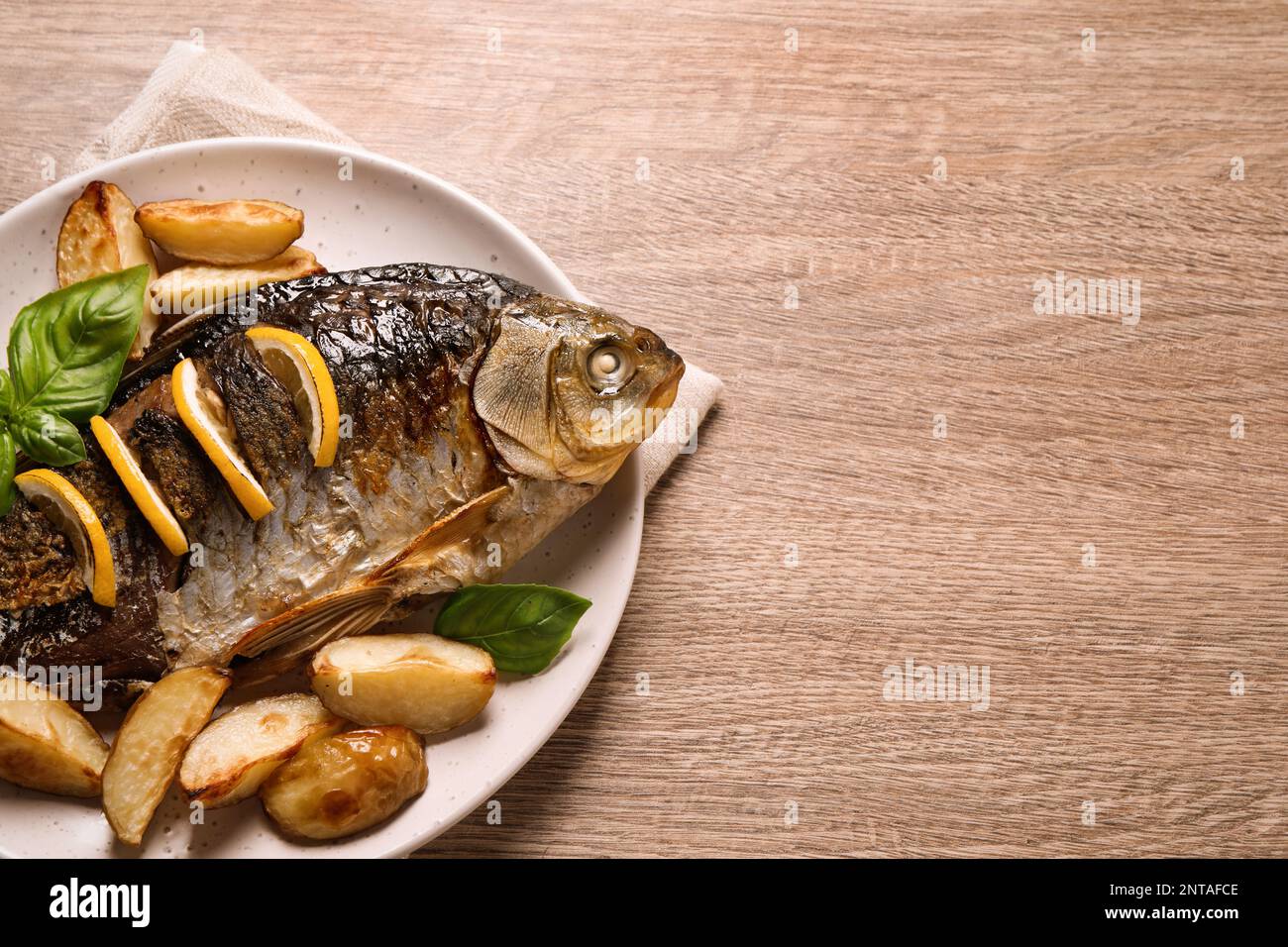 Tasty homemade roasted crucian carp with garnish on wooden table, top ...