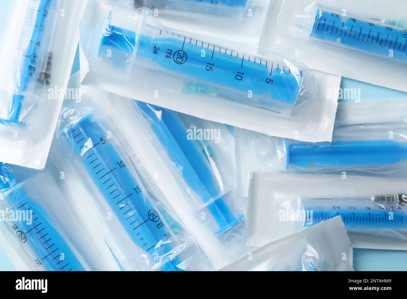 Packed disposable syringes with needles on light blue background, top ...
