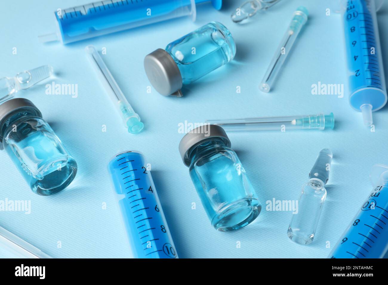 Disposable syringes with needles, ampules and vials on light blue ...