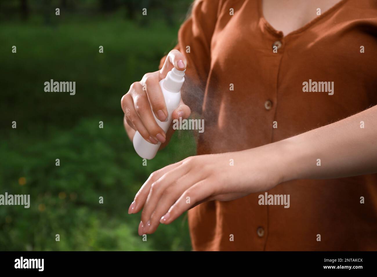 Woman applying insect repellent onto hand in park, closeup. Tick bites ...