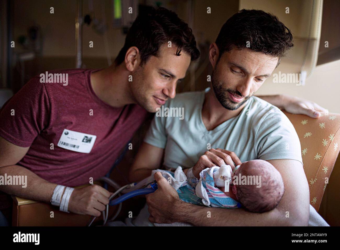 Dan Sobovitz, left, and Greg Merly hold one of their twin sons Monday ...