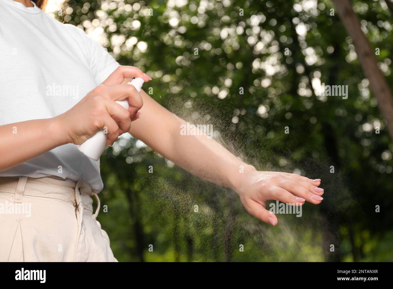 Woman applying insect repellent on arm in park, closeup. Tick bites ...