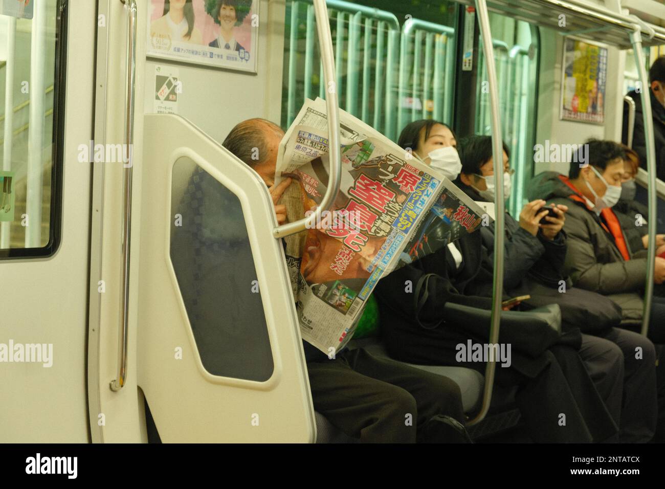 Man sitting on bustling train in Tokyo, Japan reading newspaper Stock ...