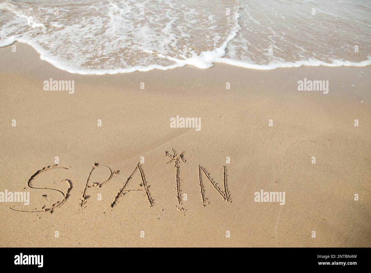 Spain lettering on the beach with wave and clear blue sea Stock Photo ...