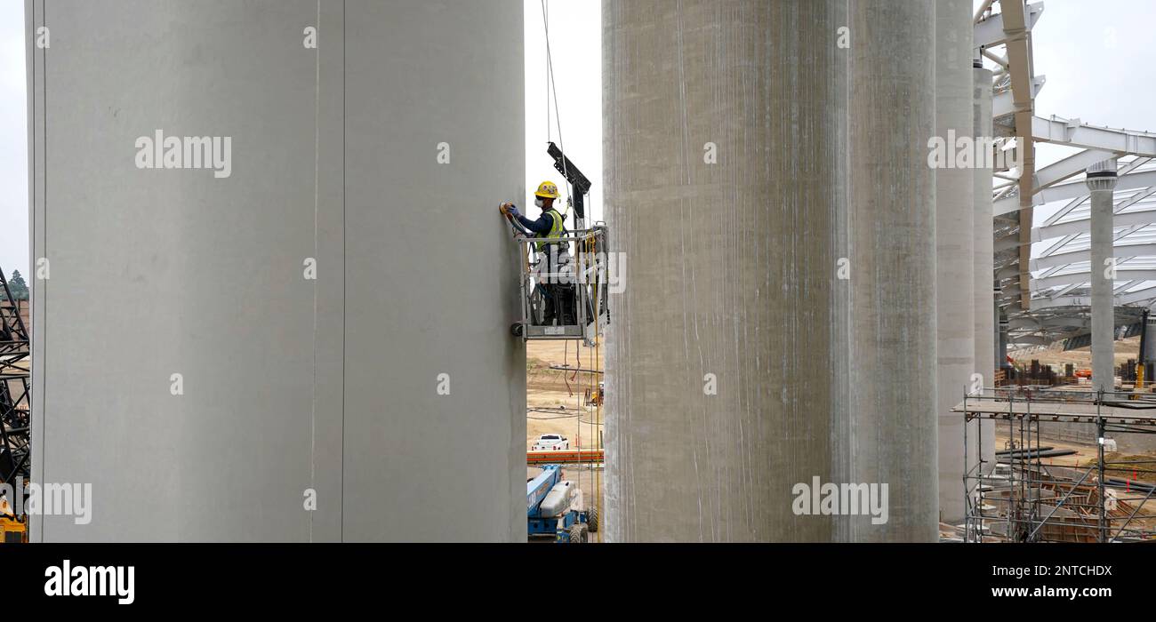 A construction worker uses a sander to smooth a concrete column at the ...