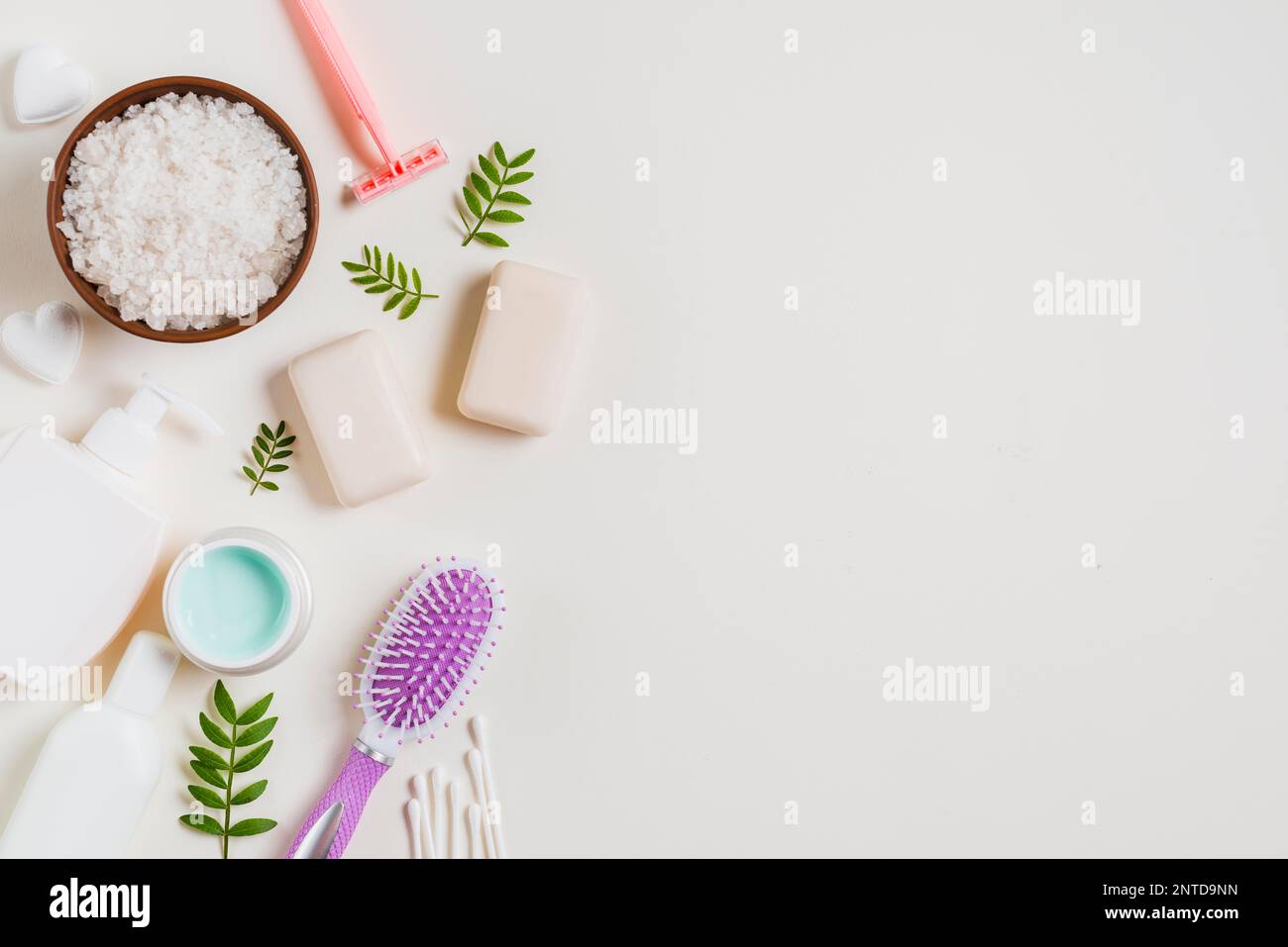 overhead view cosmetics products soap razor ear buds green leaves white ...