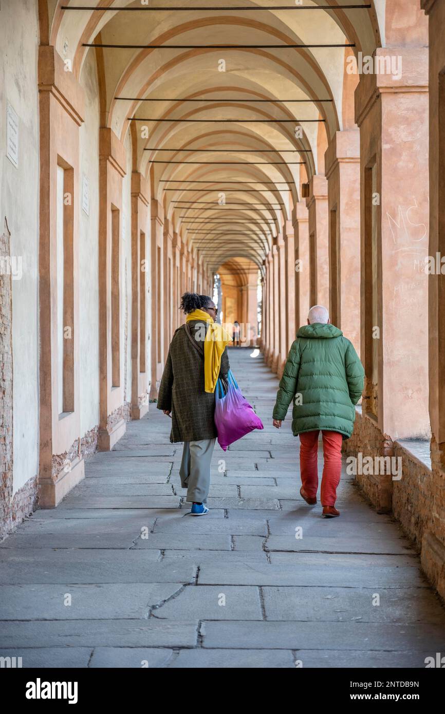 Couple walking through arcades to Colle della Guardia, longest arcade ...