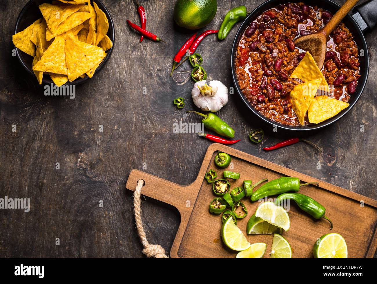Chili con carne in frying pan on dark wooden background. Ingredients ...
