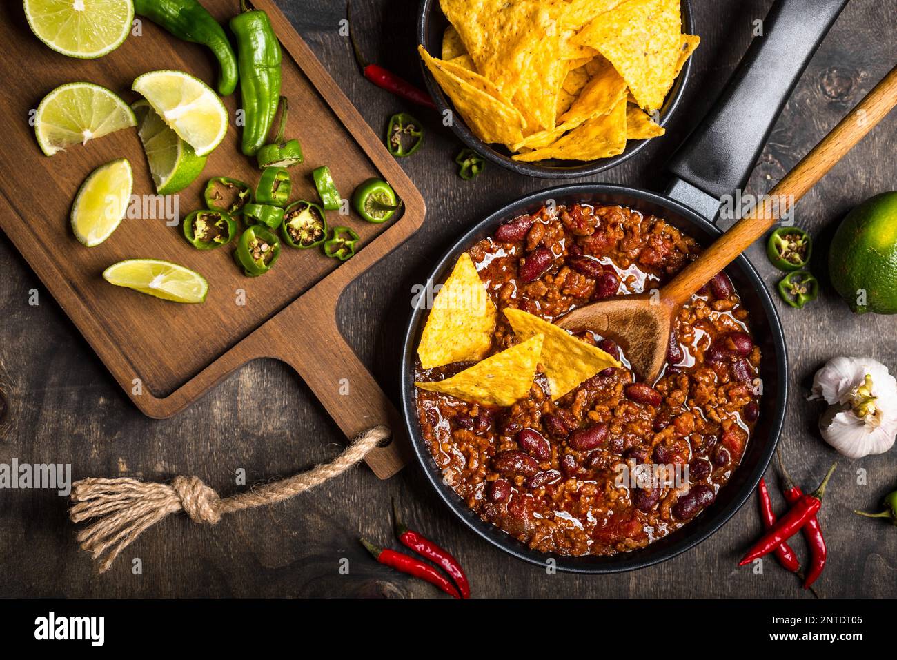 Chili con carne in frying pan on dark wooden background. Ingredients ...