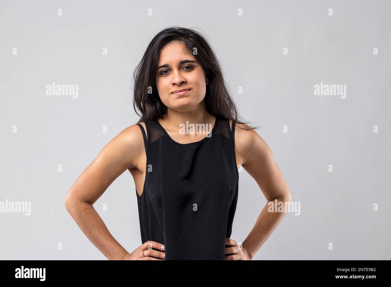 Beautiful young Indian woman with arms akimbo. She has her hands on her ...