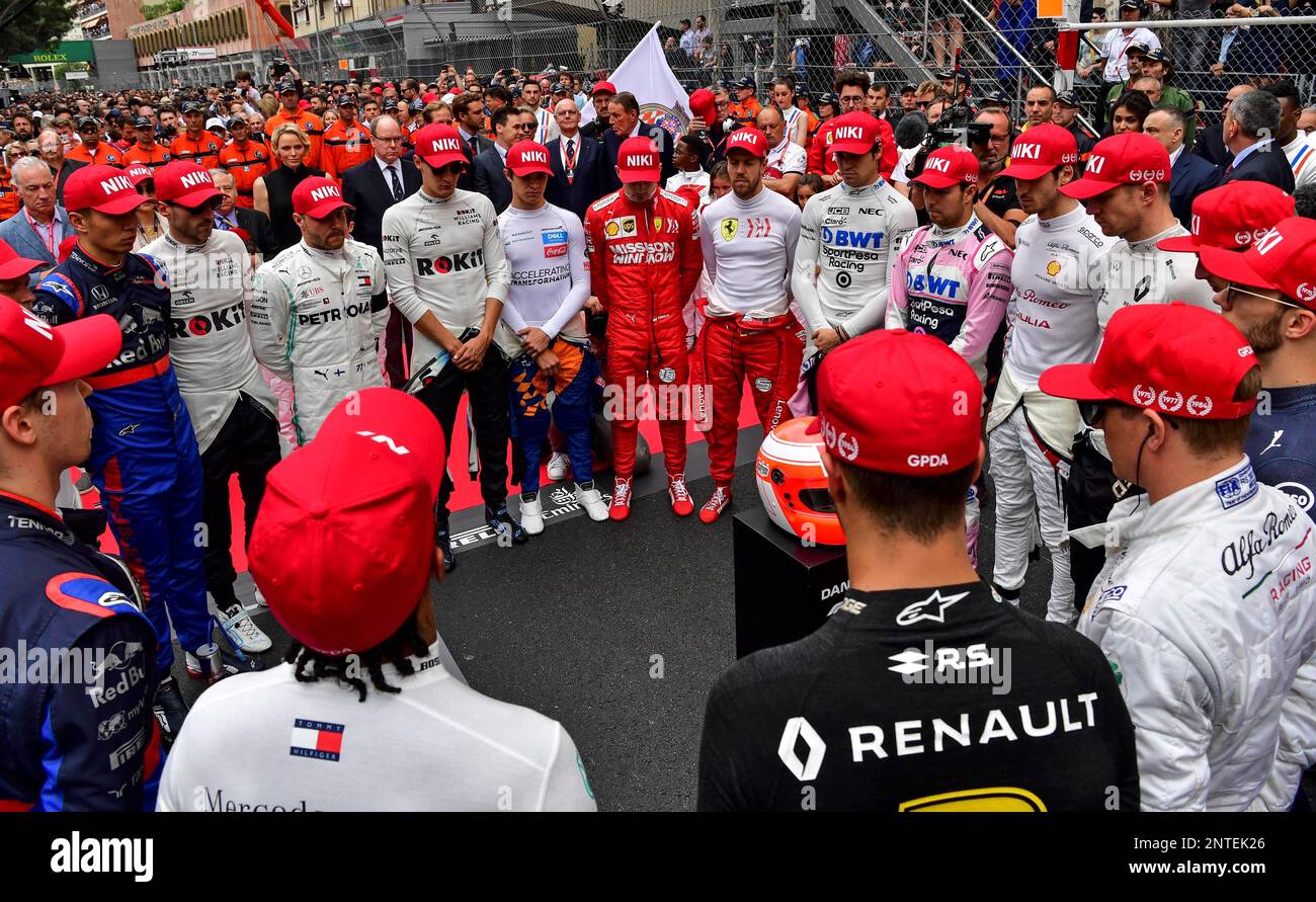 The drivers clap hands around a red helmet on a podest, reading 'Thank ...