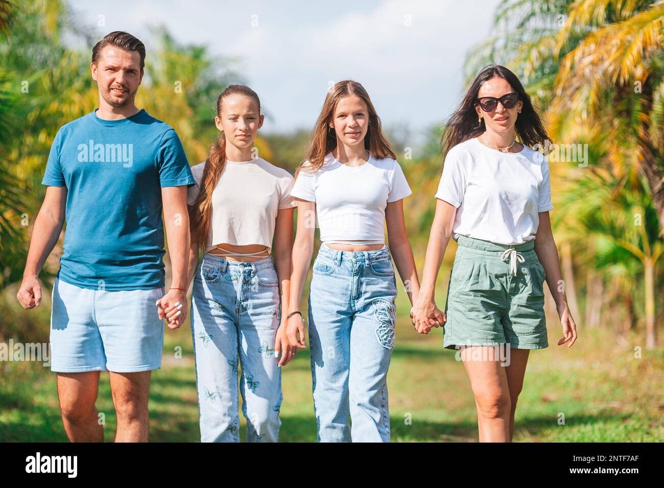 Family of four having fun among palm trees on vacation. Family vacation ...