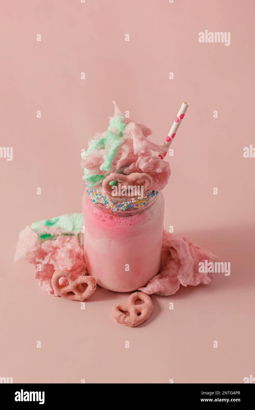 Milkshake in a glass jar covered with a cotton candy and pretzel, pink ...