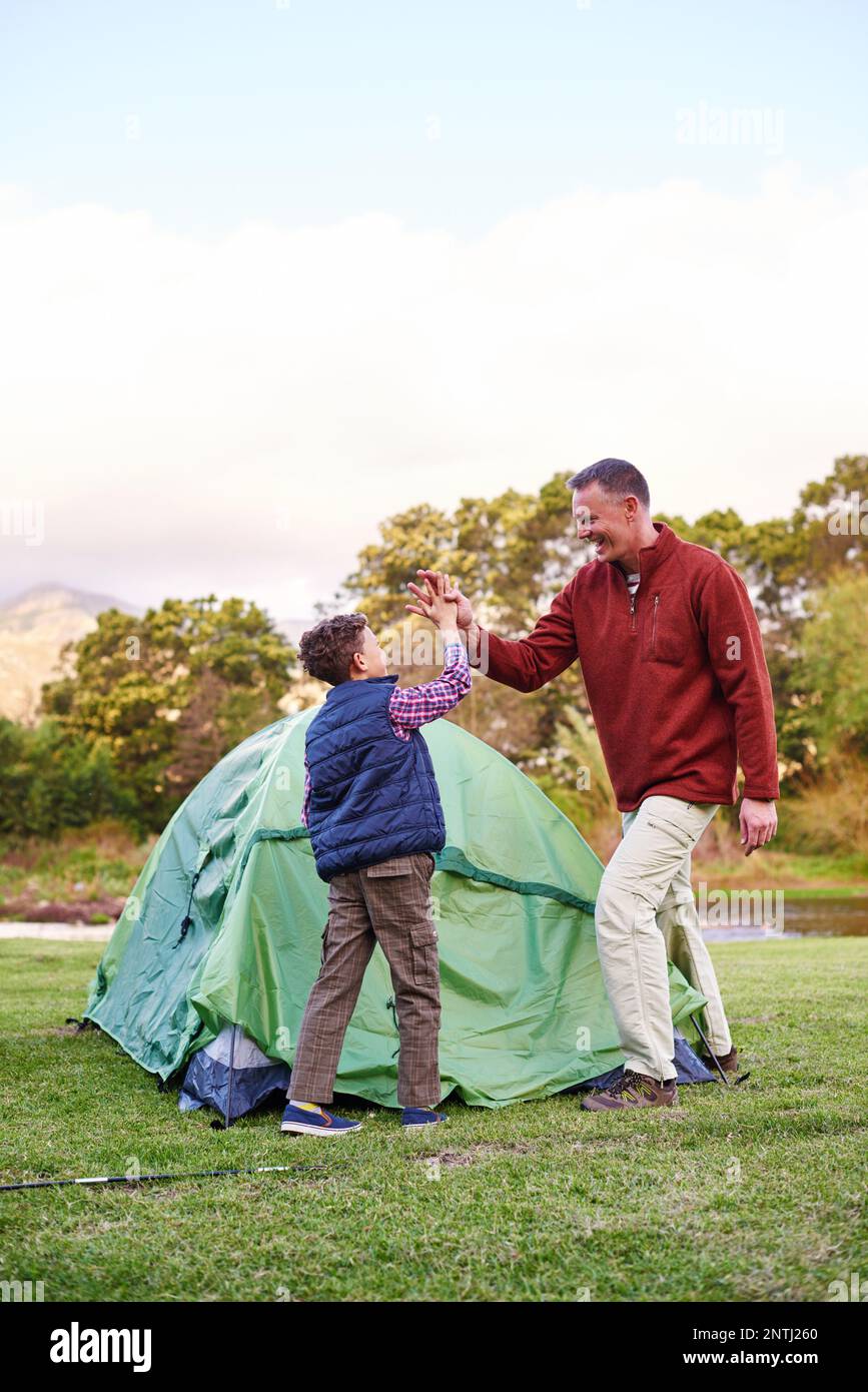 Great job. a father and son hi fiving after setting up a tent together ...