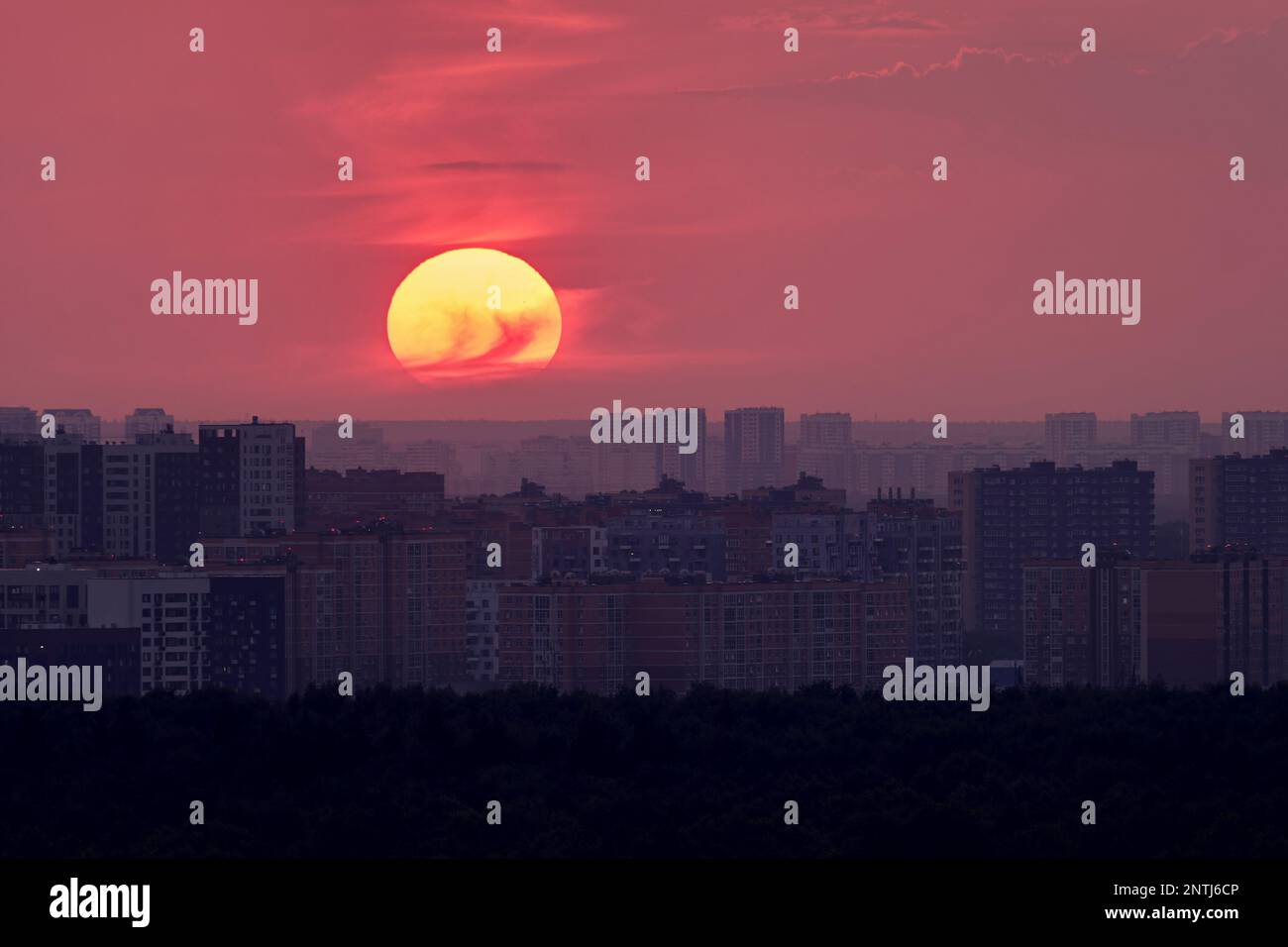 Big red sun over the roofs of city buildings, evening sunset. Cloudy ...