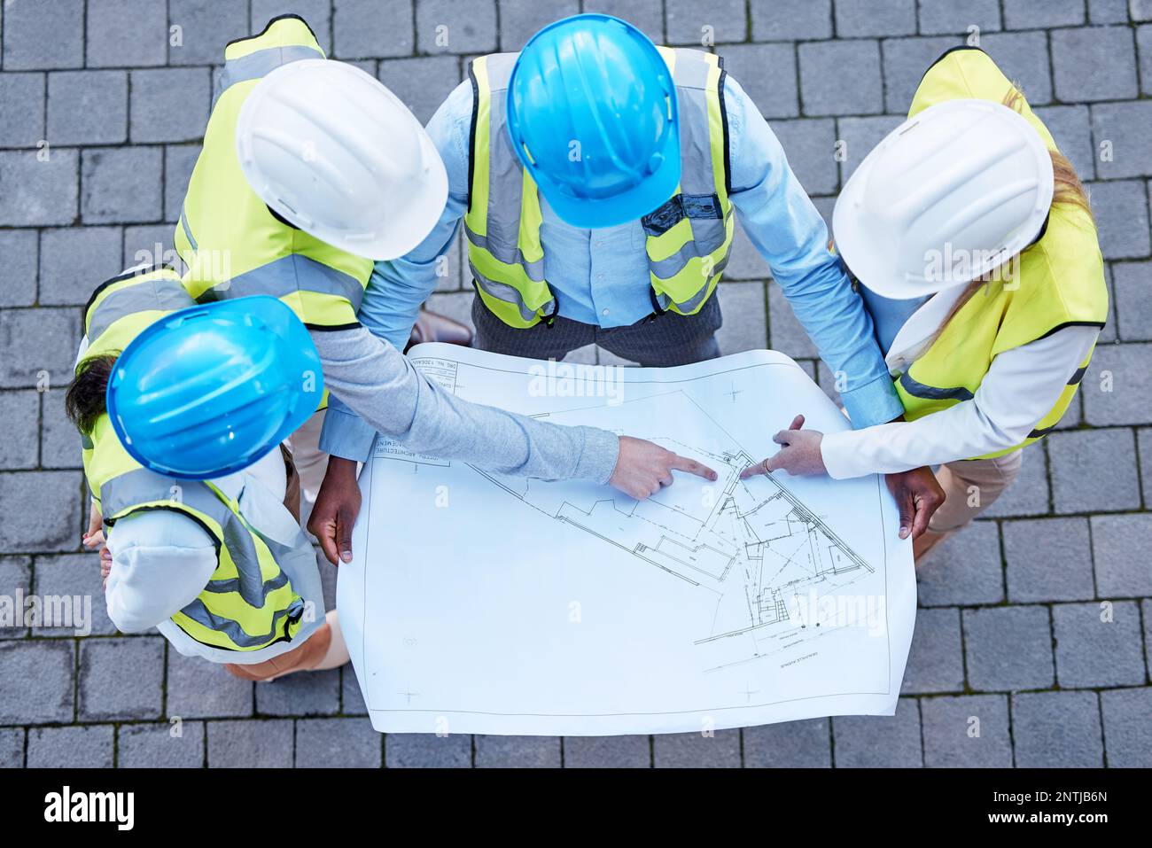 Blueprint, pointing and engineering with people on construction site from top view for planning ...