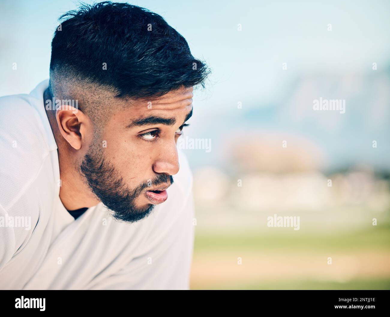 Tired, breathing and sports man at a field for training, break and ...