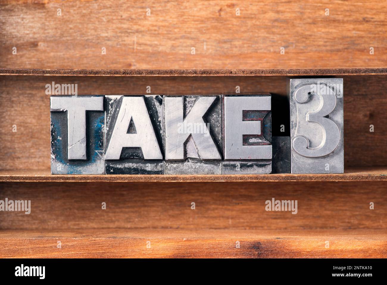 take three phrase made from metallic letterpress type on wooden tray ...