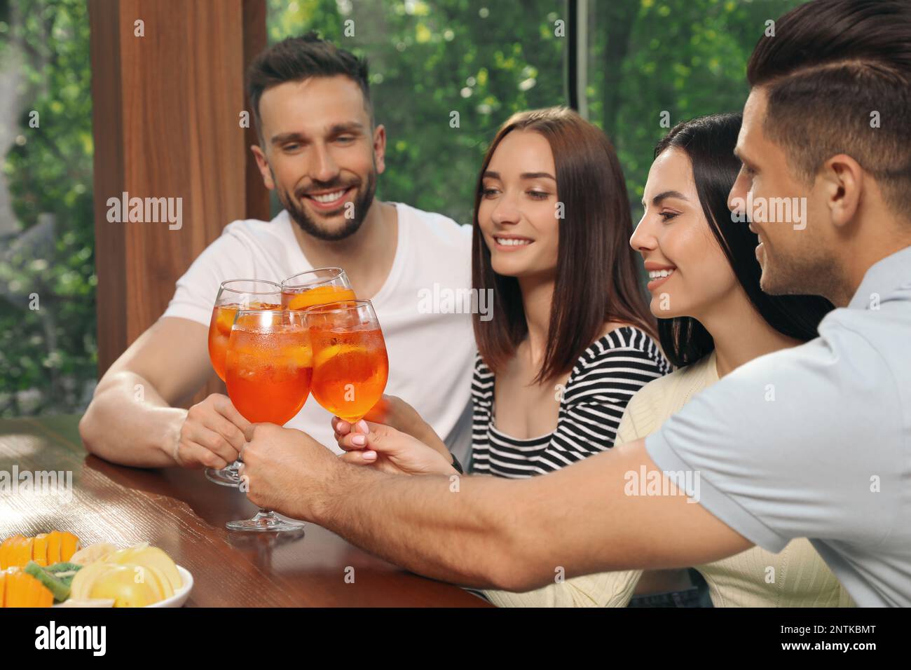 Friends clinking glasses of Aperol spritz cocktails at table Stock ...